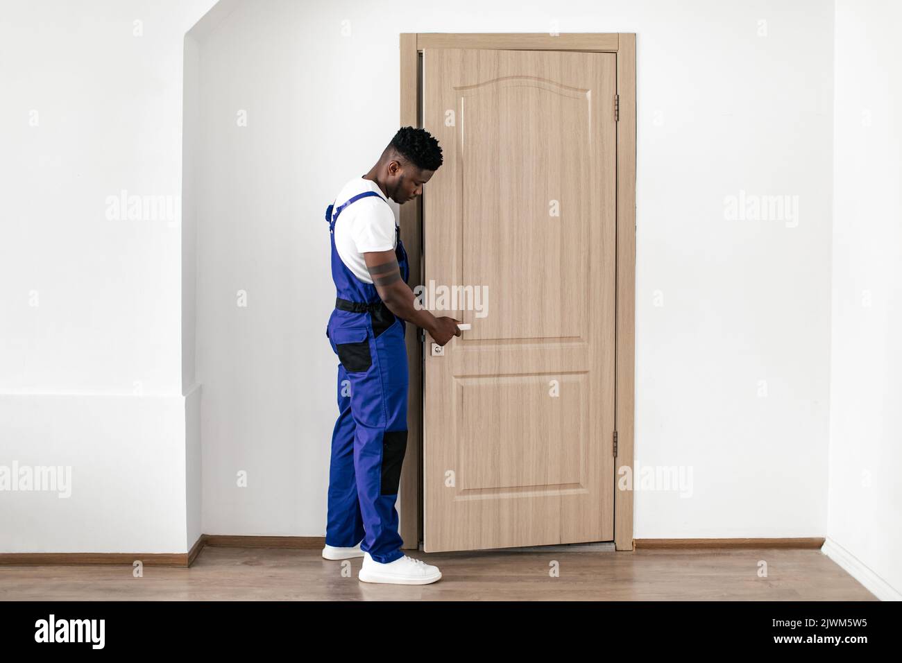 Black Repairman Installing Entry Door, Fixing Lock And Handle Indoor ... Black Repairman Installing Entry Door, Fixing Lock And Handle Indoor ...