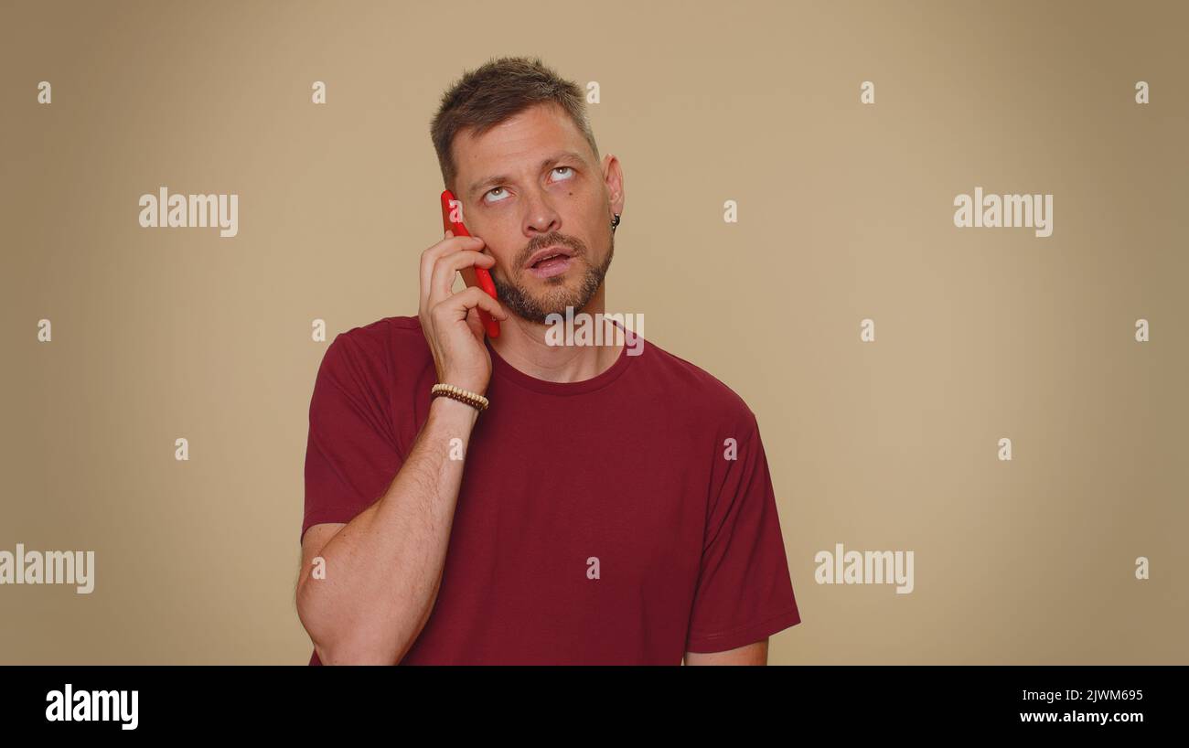 Tired young man in red t-shirt making online conversation speaks on ...