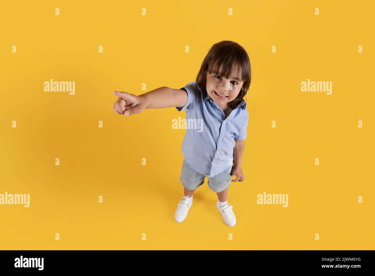 Top view portrait of cute little boy pointing aside at free space and ...