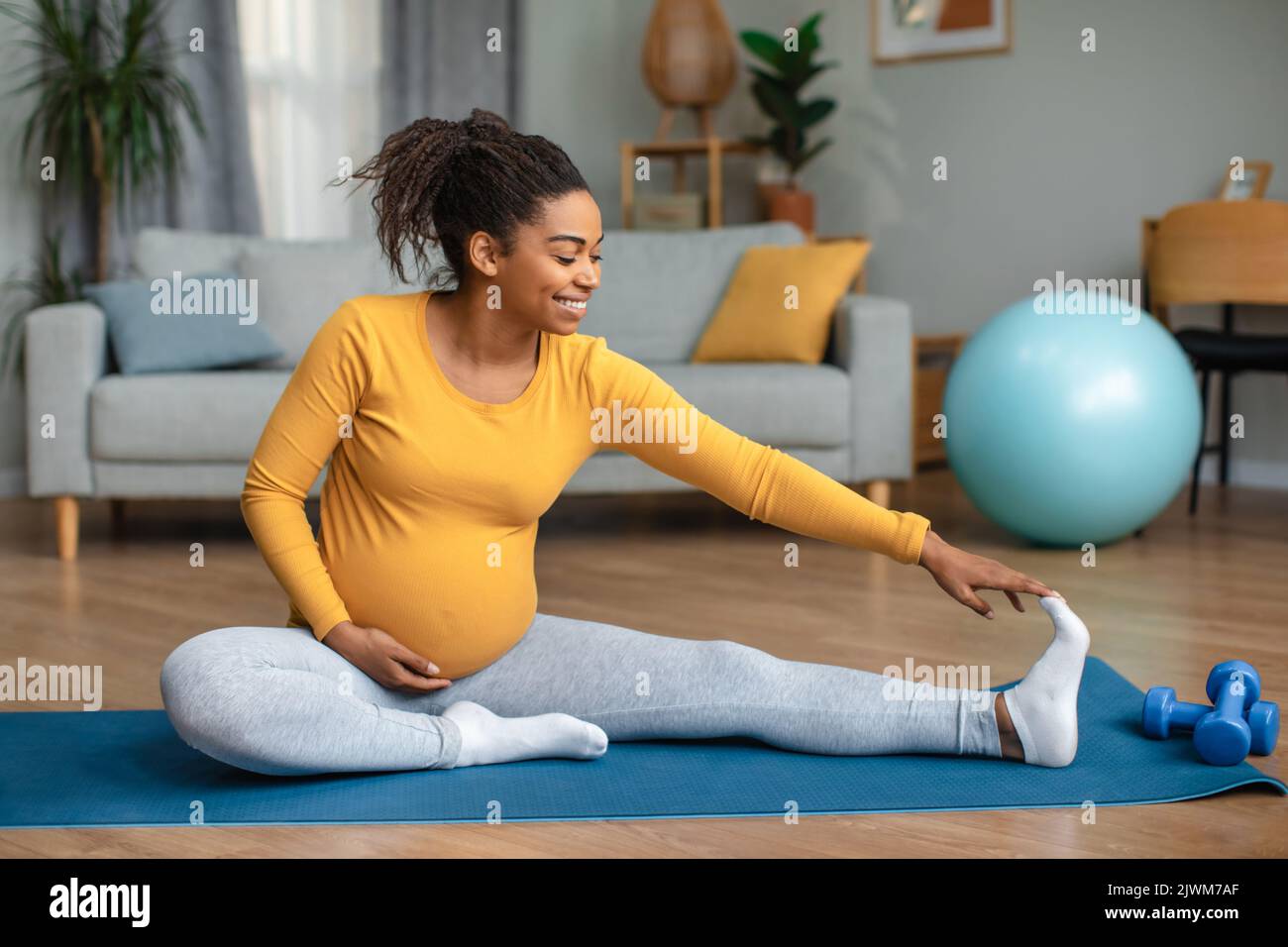 Smiling Young Pregnant African American Female With Big Belly Doing Leg