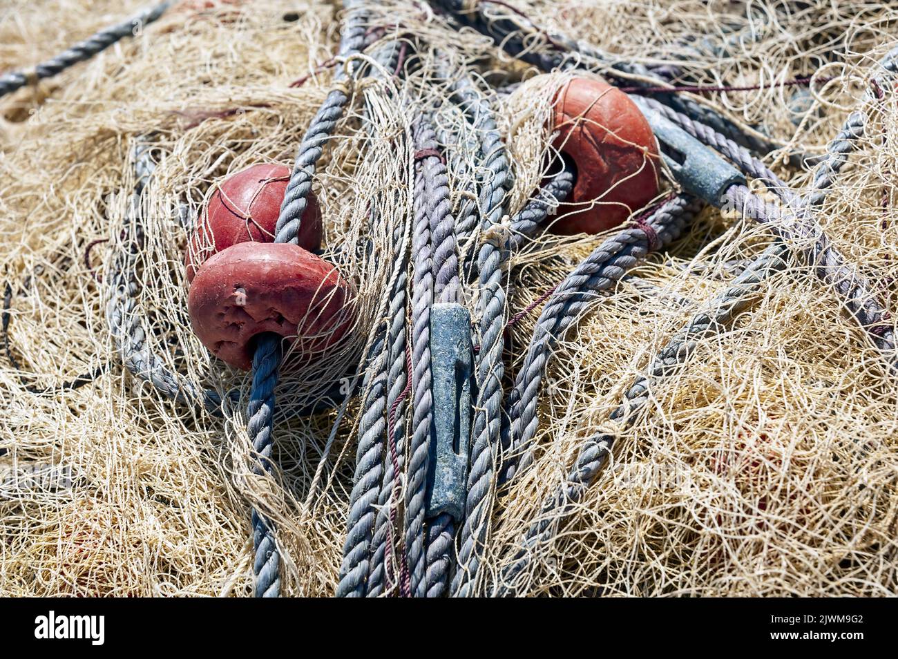 Heap of drying yellow fishing net with red floats at Myconos port ...