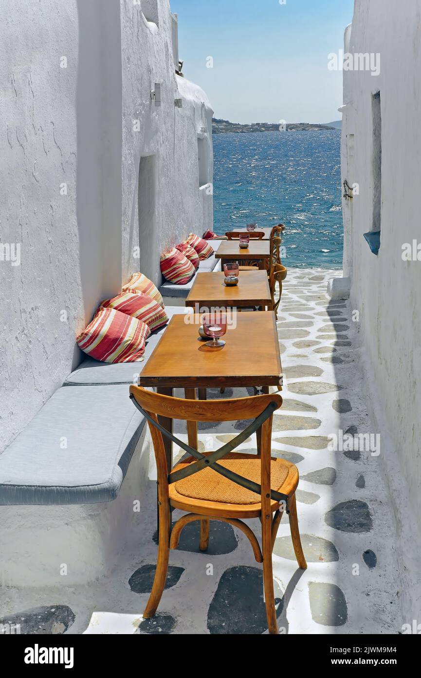 The narrow path to the sea with furniture at Mykonos island in Greece ...
