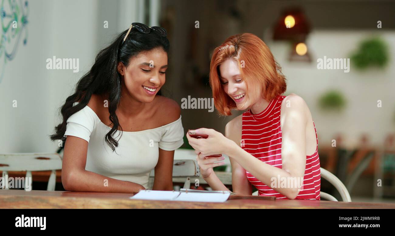 Friend showing cellphone screen to girlfriend, multi-ethnic diverse ...