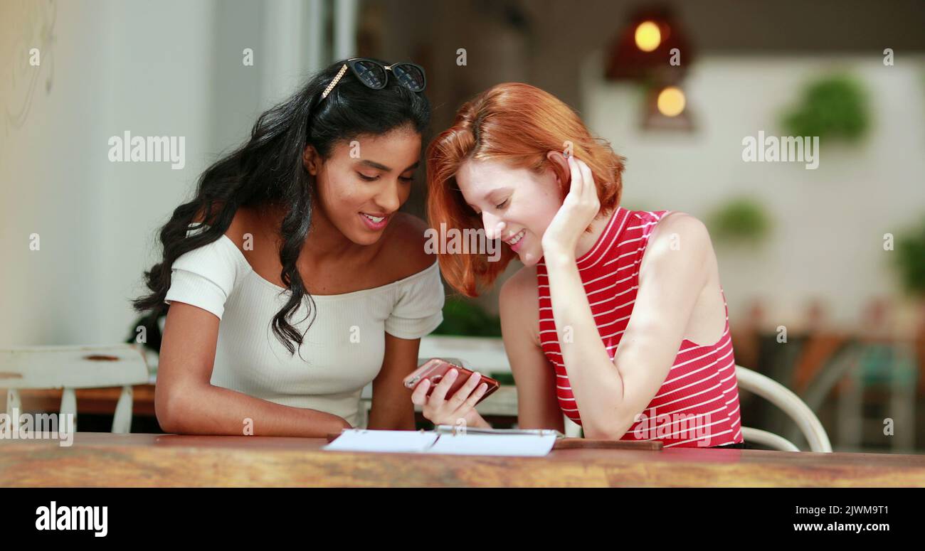 Friend showing cellphone screen to girlfriend, multi-ethnic diverse ...