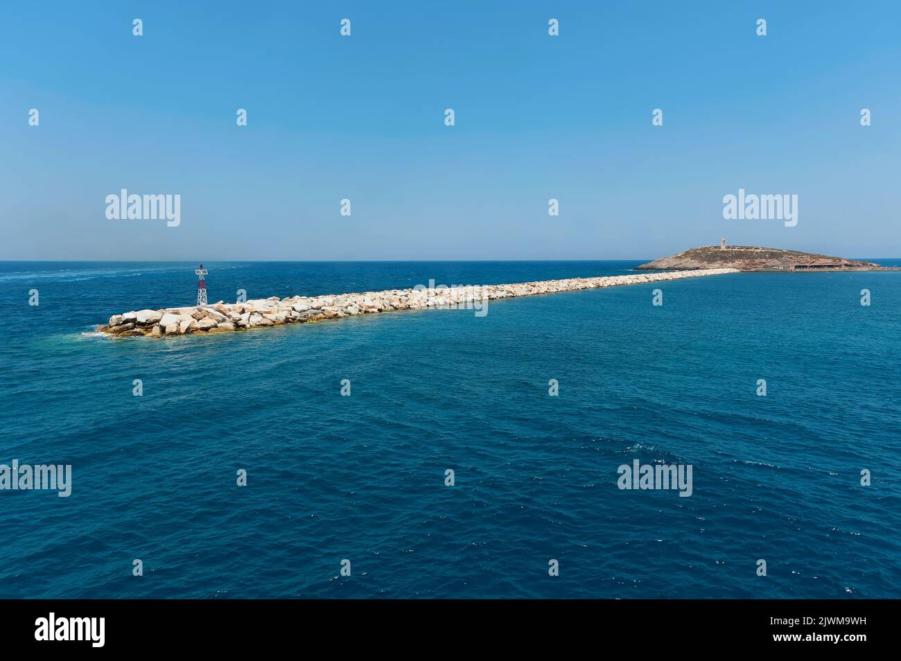 Seascape with small lighthouse on breakwater leading to islet of ...