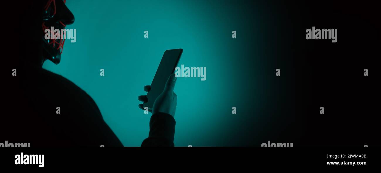 Digital security Concept. Anonymous hacker with mask holding smartphone ...
