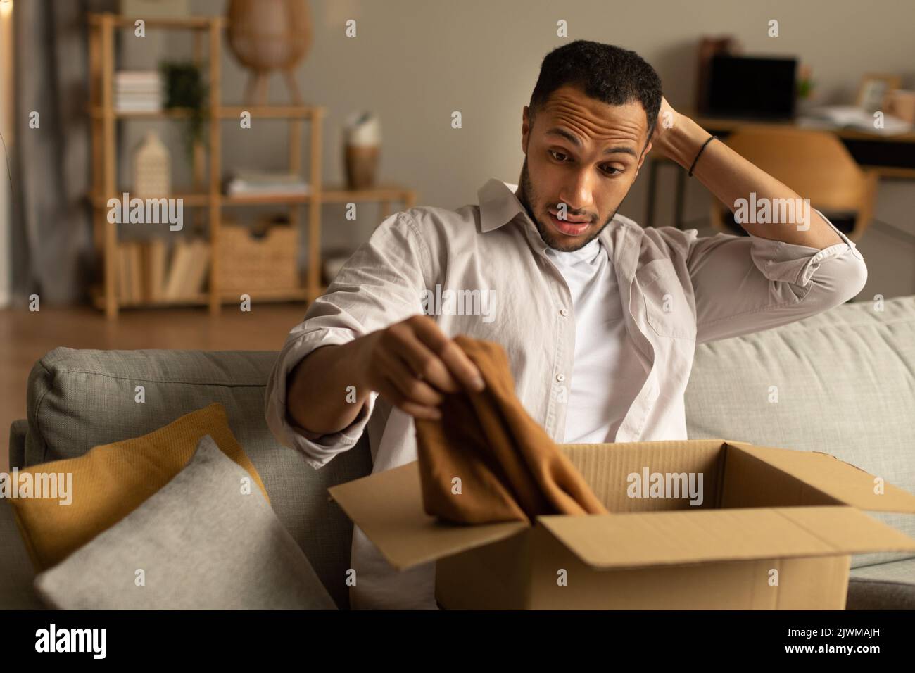Dissatisfied buyer. Frustrated black man unboxing package after ...