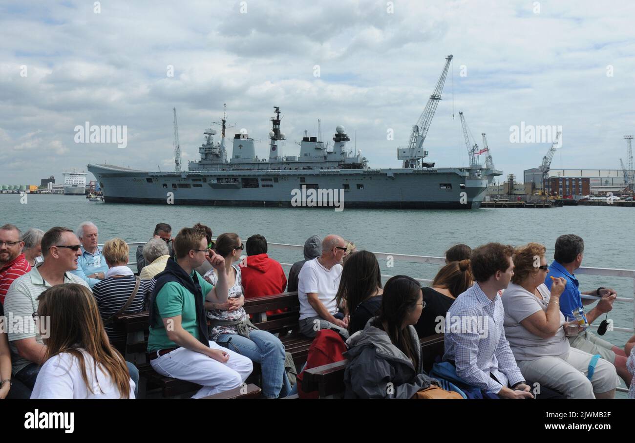 PASSENGERS ON A HARBOUR CRUISE SAIL PAST HMS ILLUSTRIOUS IN PORTSMOUTH ...