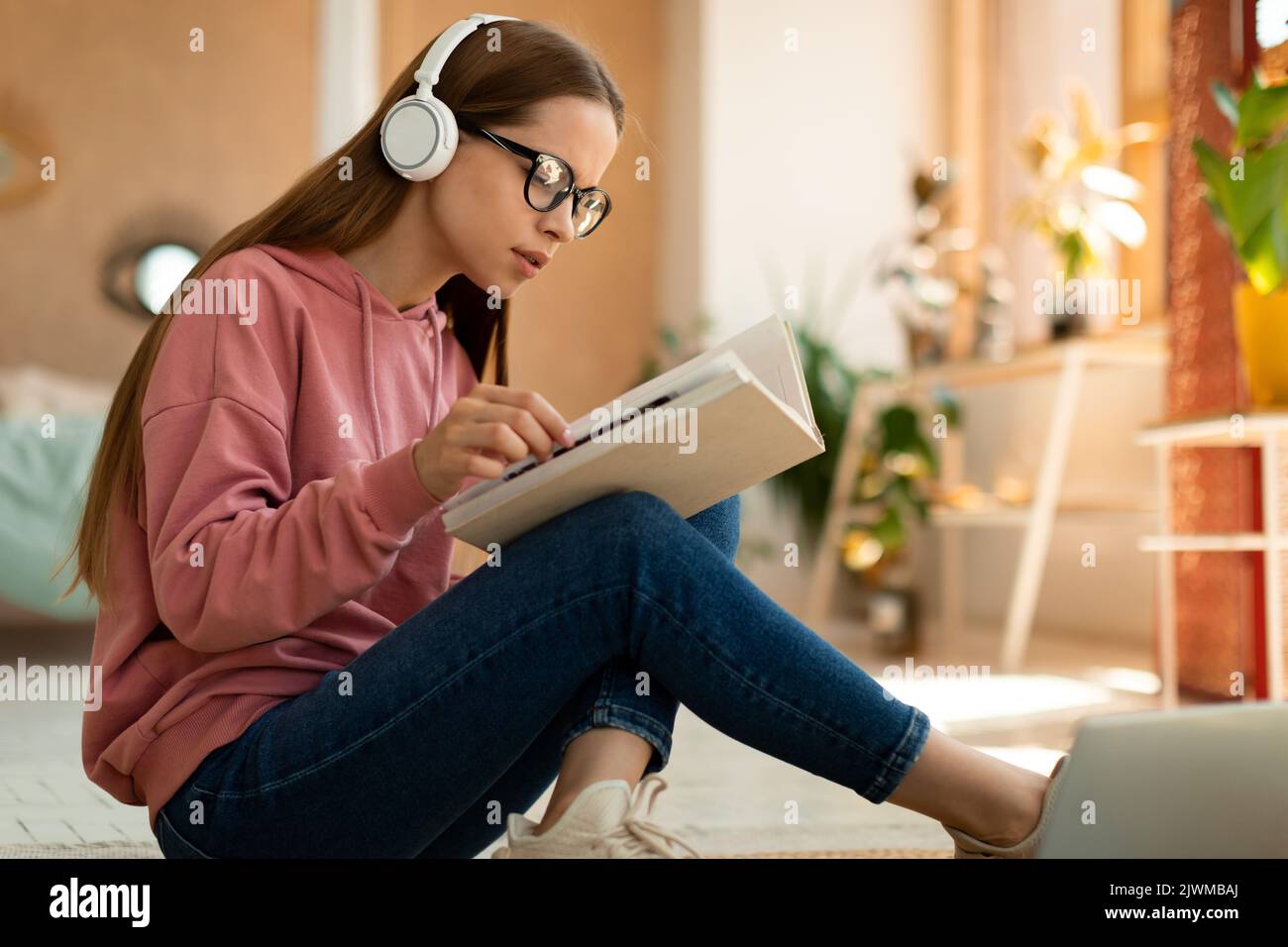 Distance education concept. Smart teen girl sitting on floor with book ...
