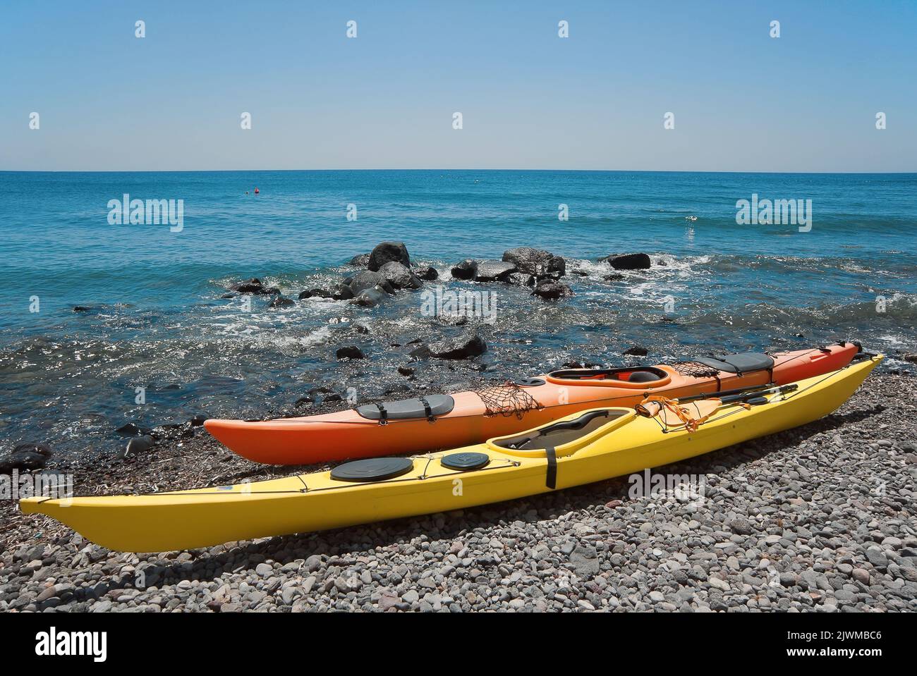 The yellow and orange kayaks on the black sand beach of Santorini ...