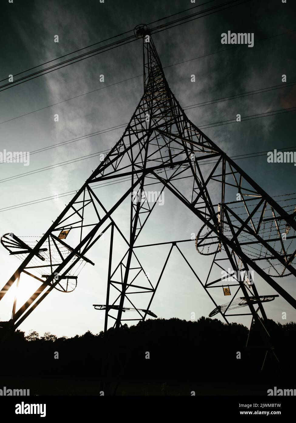 electric power supply pylon silhouetted with strong back light from sun ...