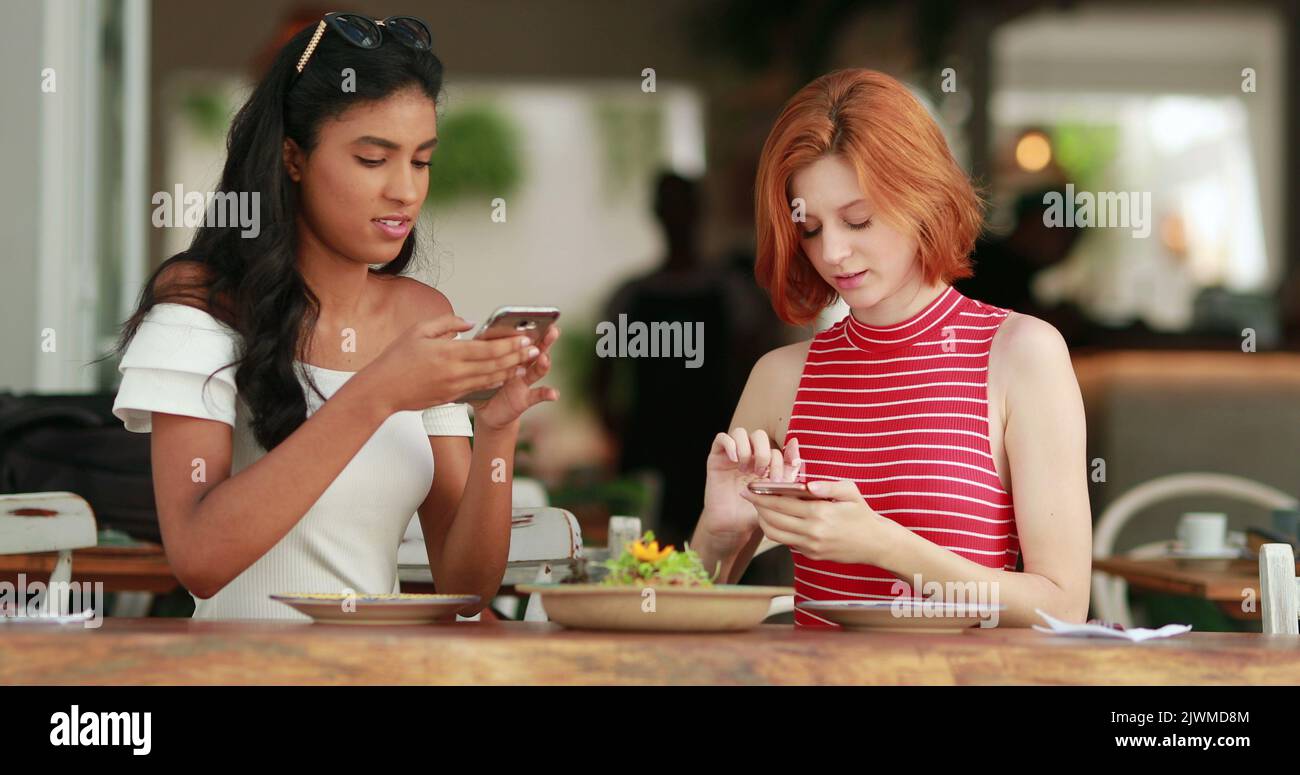 Diverse young women taking photo of food plate showing scren Stock ...