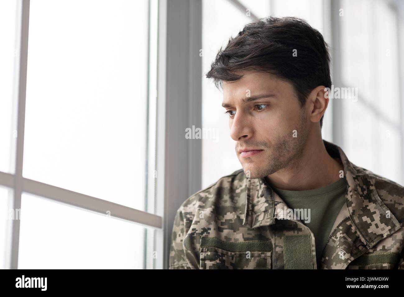 Serious young man soldier looking through the window Stock Photo - Alamy