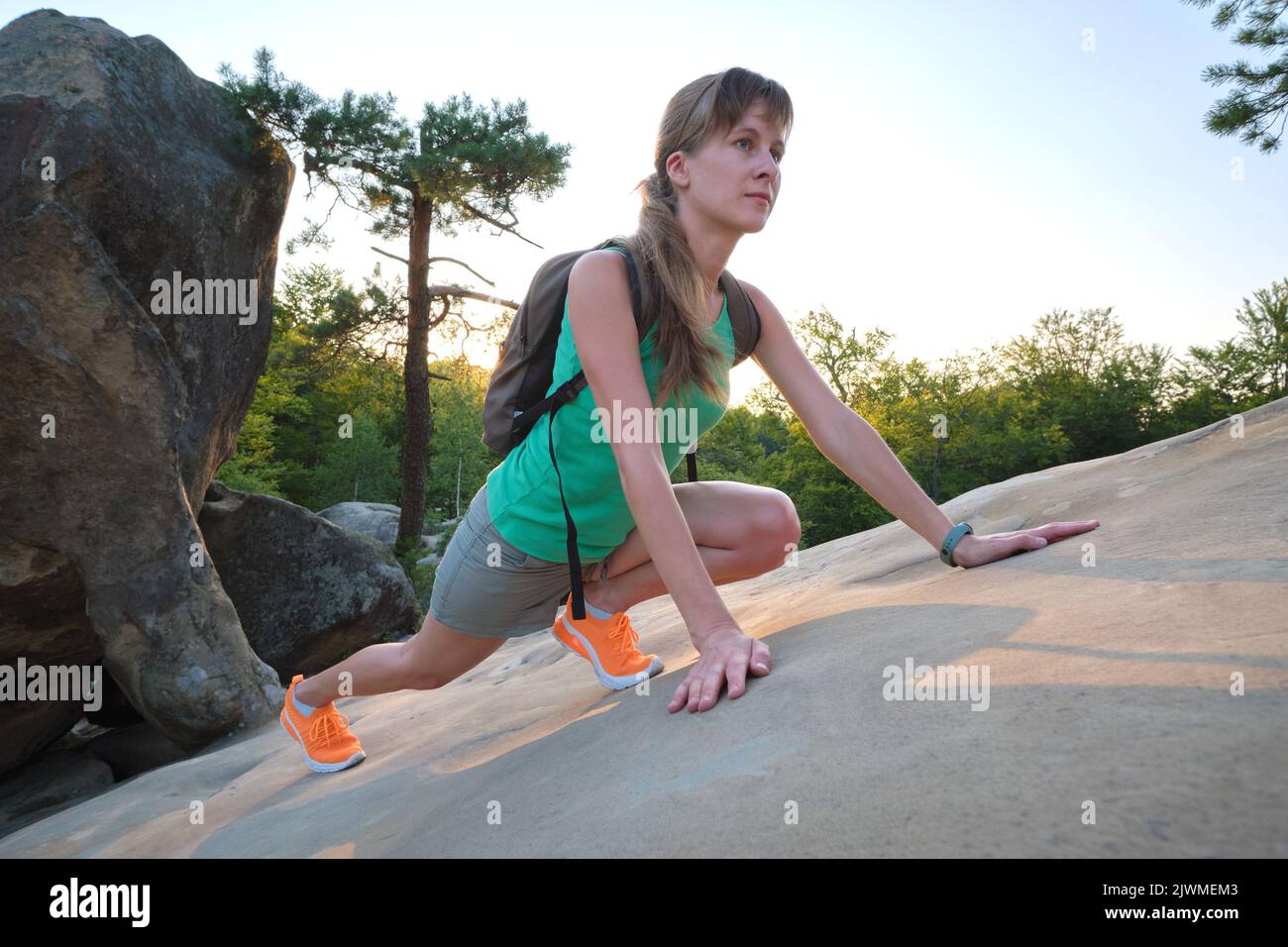 Hiker woman clambering on rocky mountain footpath in evening nature ...