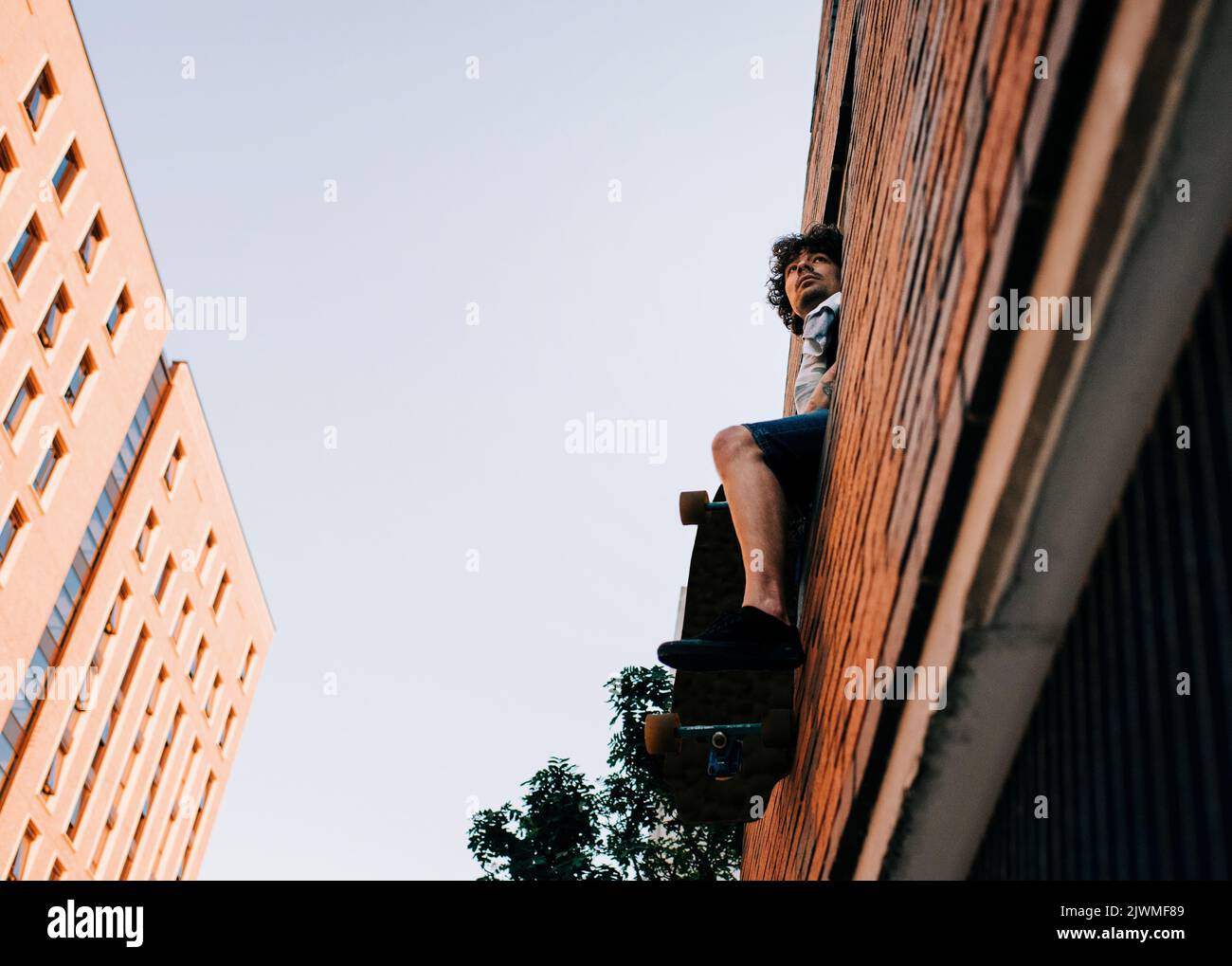 man sat in the window of a building with his skateboard at sunset Stock ...