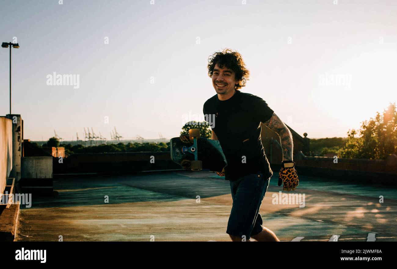 candid portrait of man running with his skateboard at sunset Stock ...