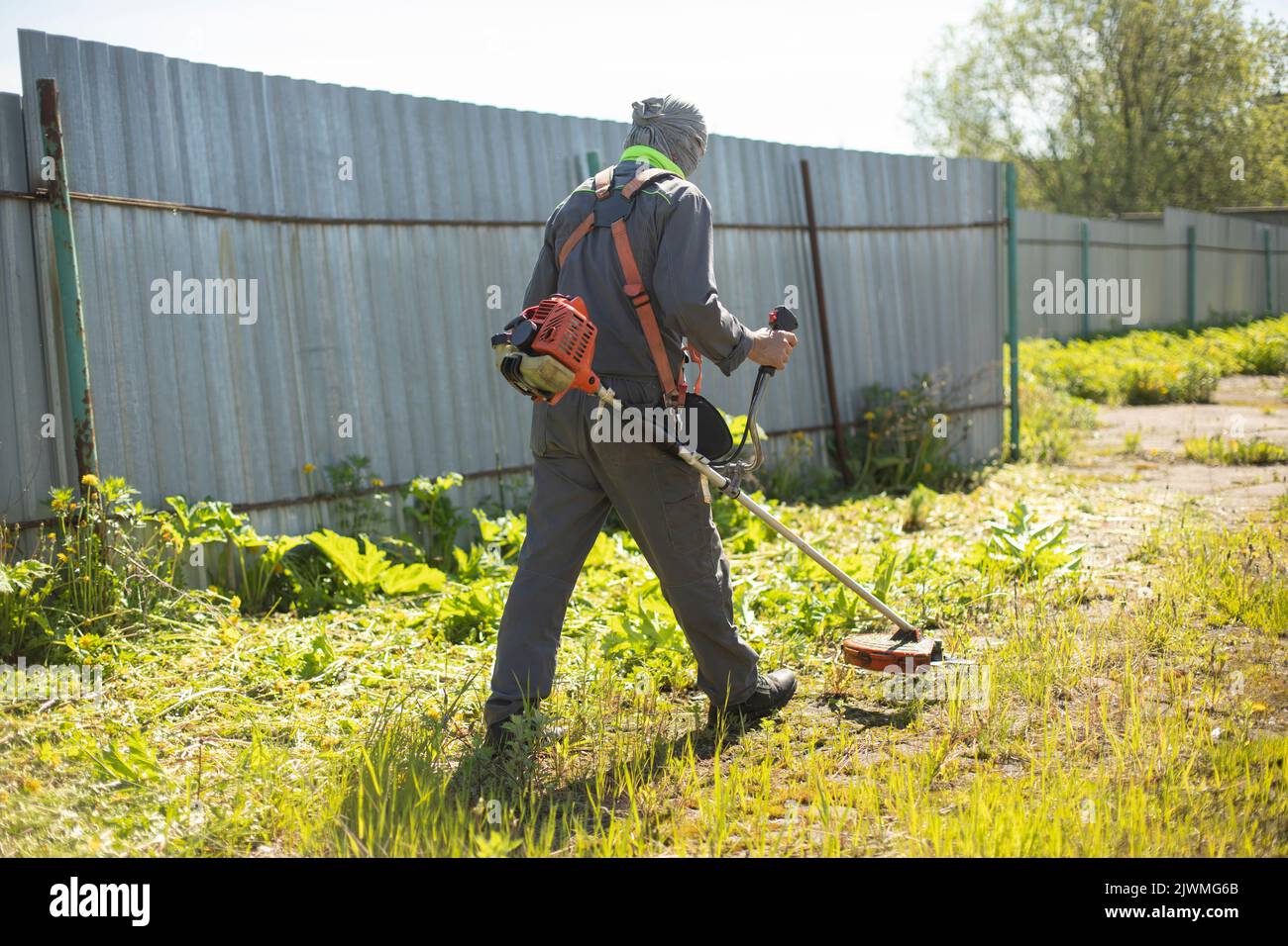 worker mows lawn. Gardener with gasoline-powered lawn mower Stock Photo ...