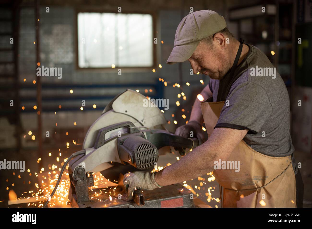Man cuts metal in workshop. Men's work in garage. Production details ...