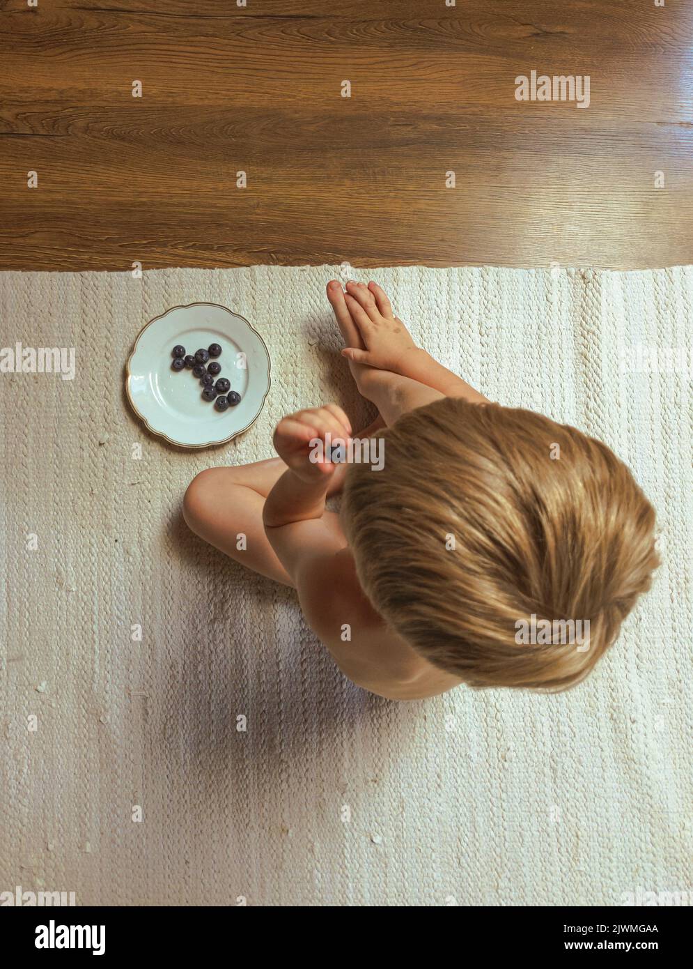 A child on the floor is eating berries Stock Photo - Alamy