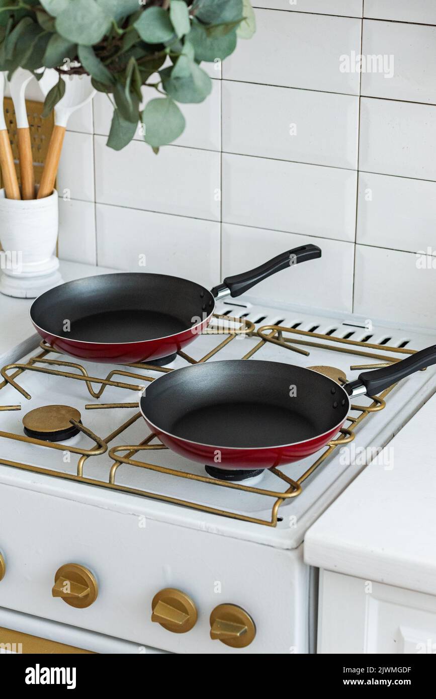frying pans on a gas stove in a bright kitchen Stock Photo - Alamy