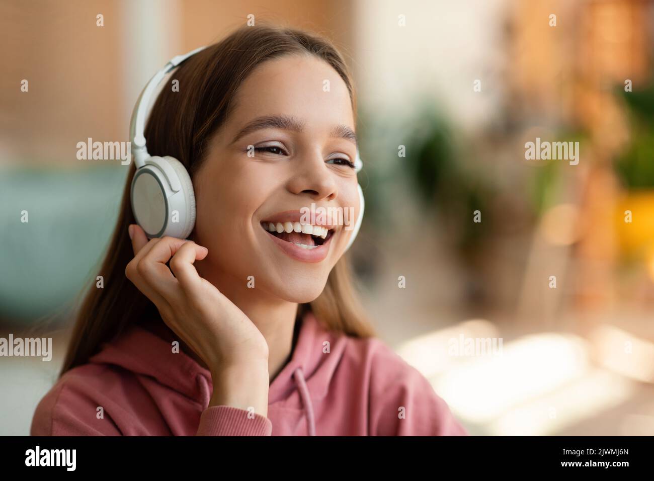Portrait of happy teen girl in wireless headphones smiling, listening ...