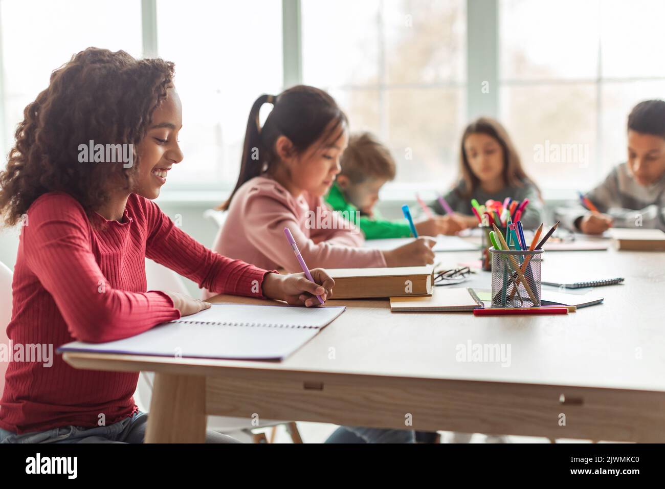 African American School Girl Writing Learning Sitting In Classroom ...