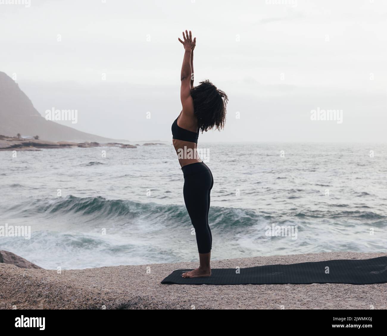 Woman practicing Urdhva Hastasana pose by ocean. Slim female standing ...