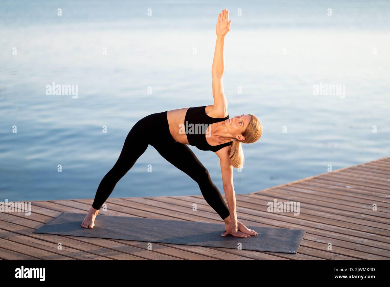 Sporty Middle Aged Woman Practicing Yoga Outdoors, Standing In Triangle ...