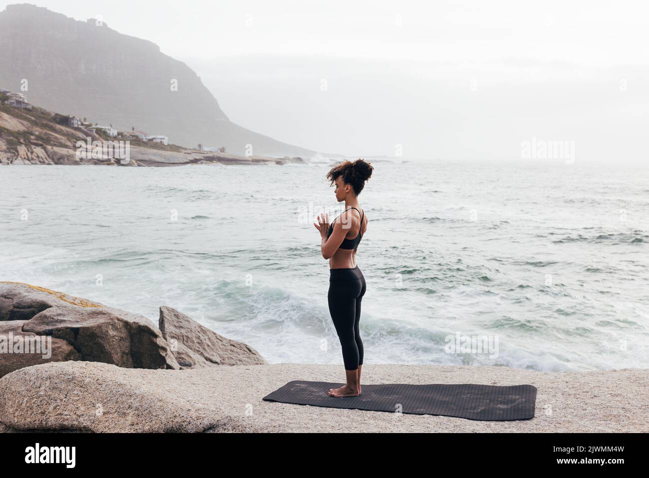 Slim female standing on mat with folded hands. Woman relaxing in ...