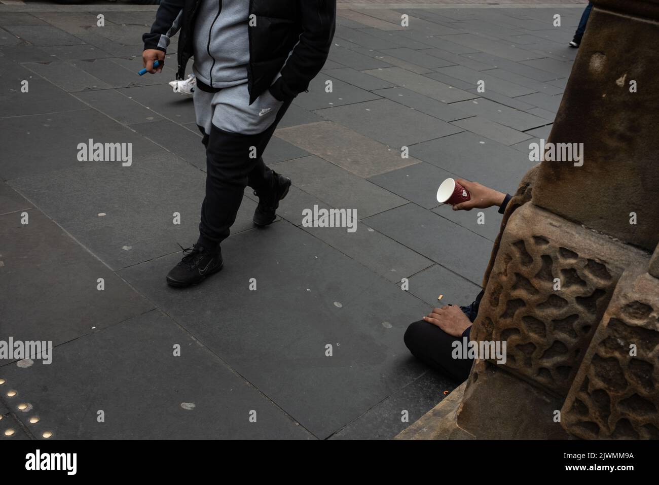 Man holding out disposable coffee cup as he begs for money, during the ...