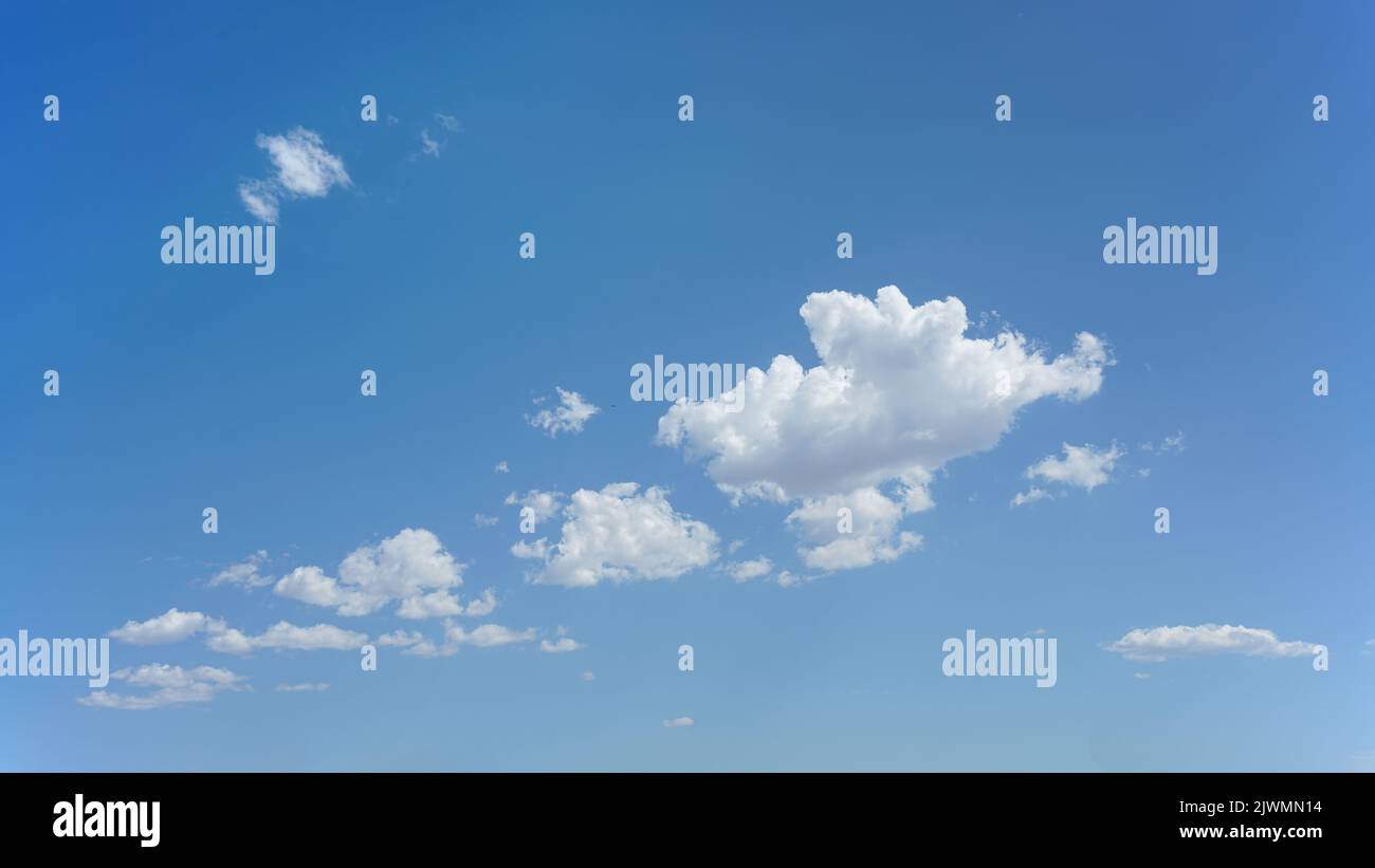 Sparse puffy clouds and blue sky for background use or sky substitution ...