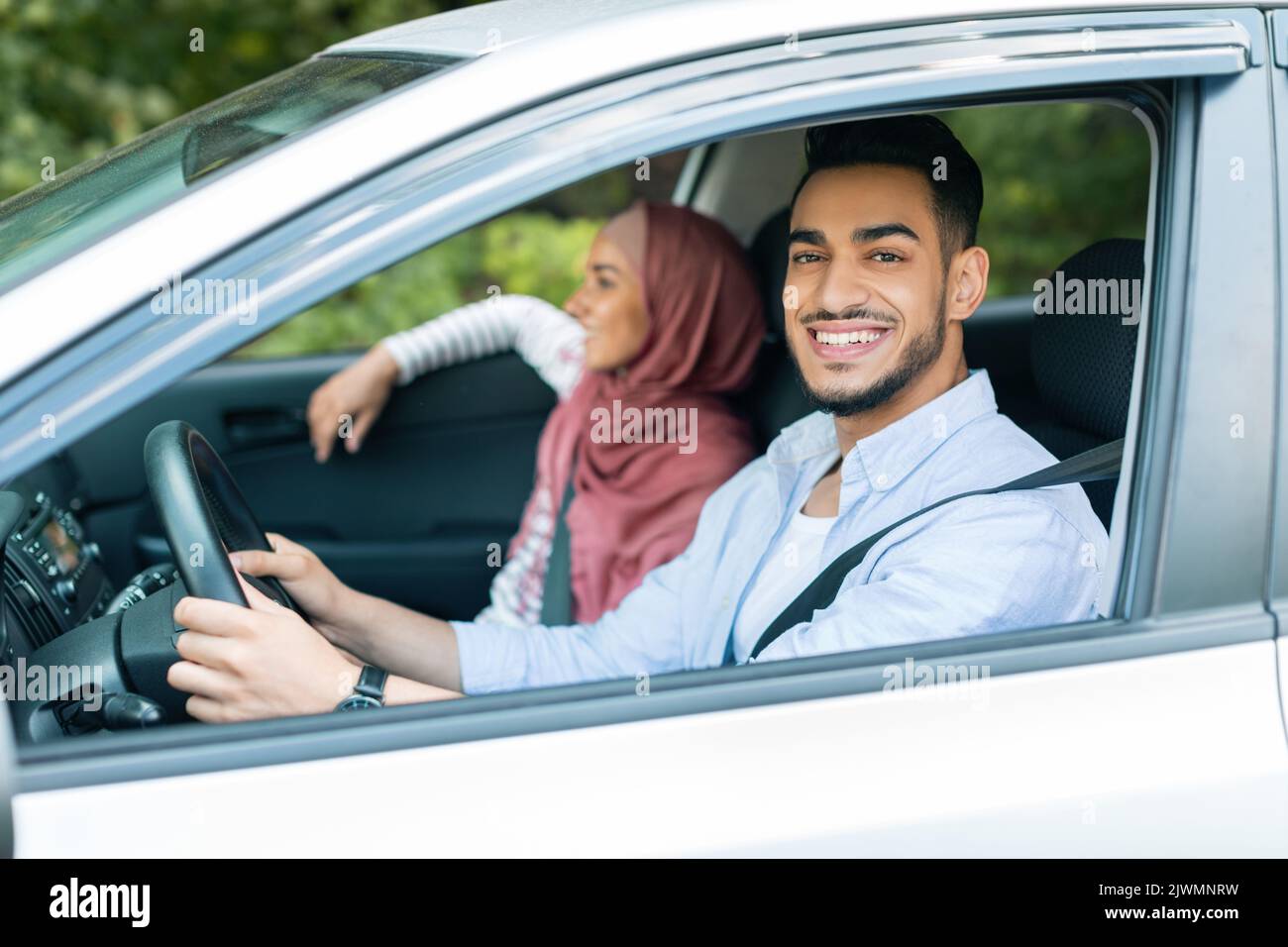 Satisfied millennial arab male driving, looks at camera, rides with his ...