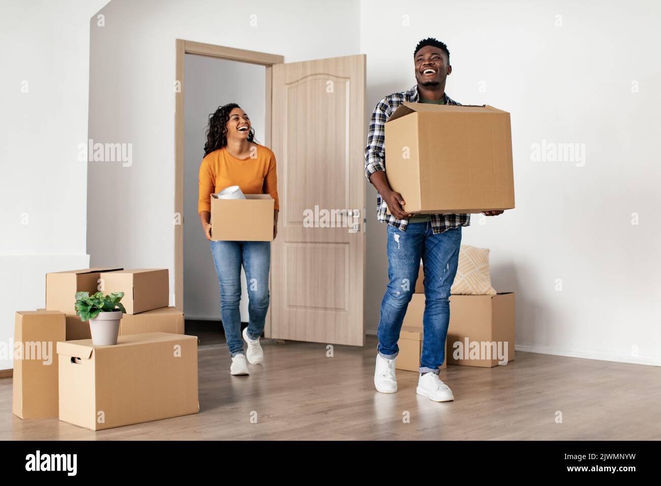 Excited African Couple Carrying Moving Boxes Looking At New House Stock ...