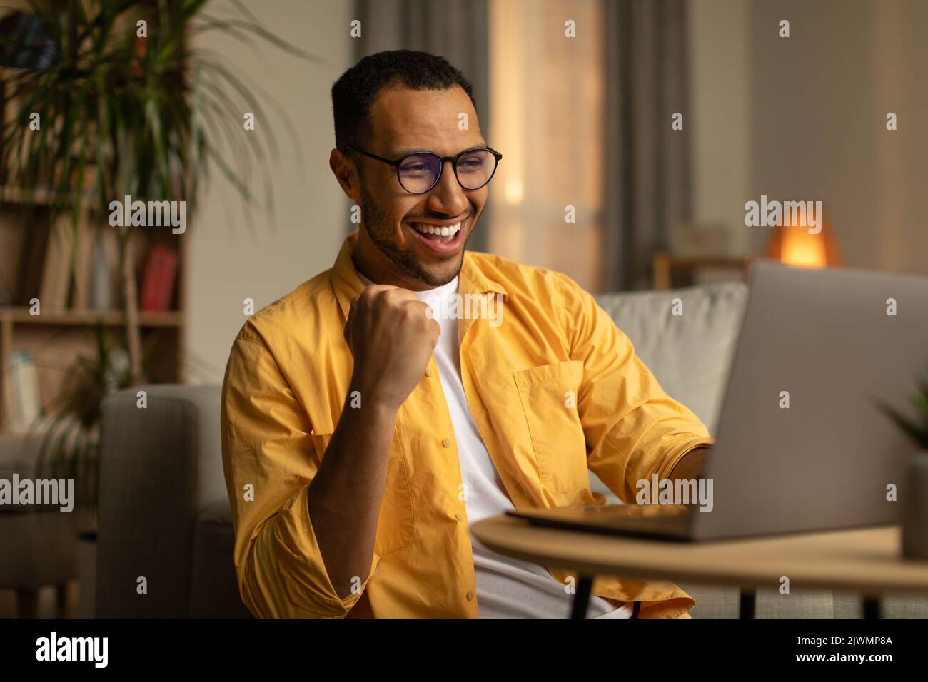 Joyful millennial black man with laptop celebrating online win or work ...