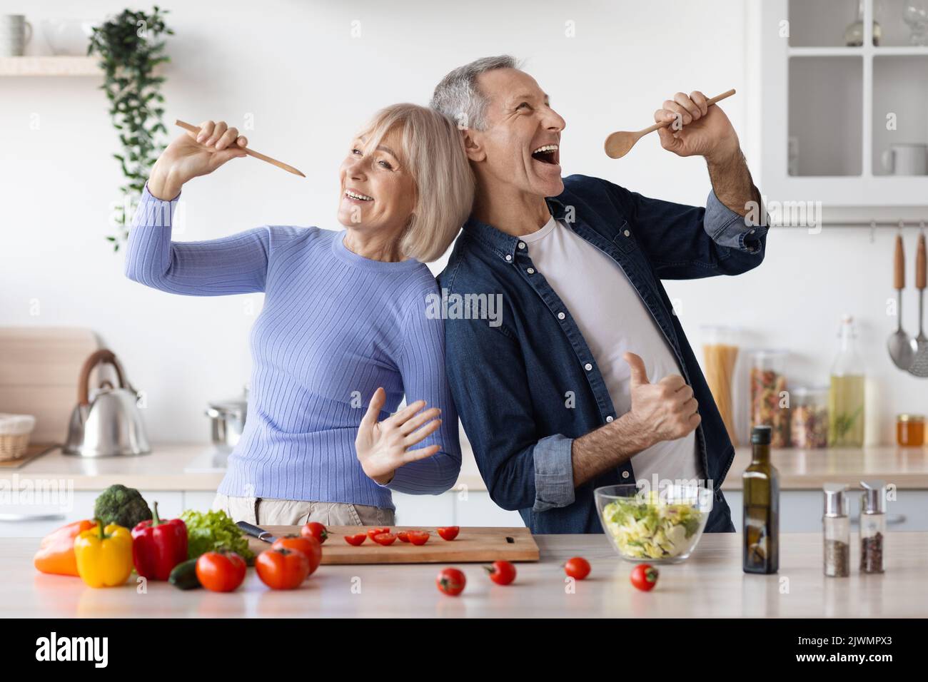 Senior husband and wife having fun while cooking, singing songs Stock ...