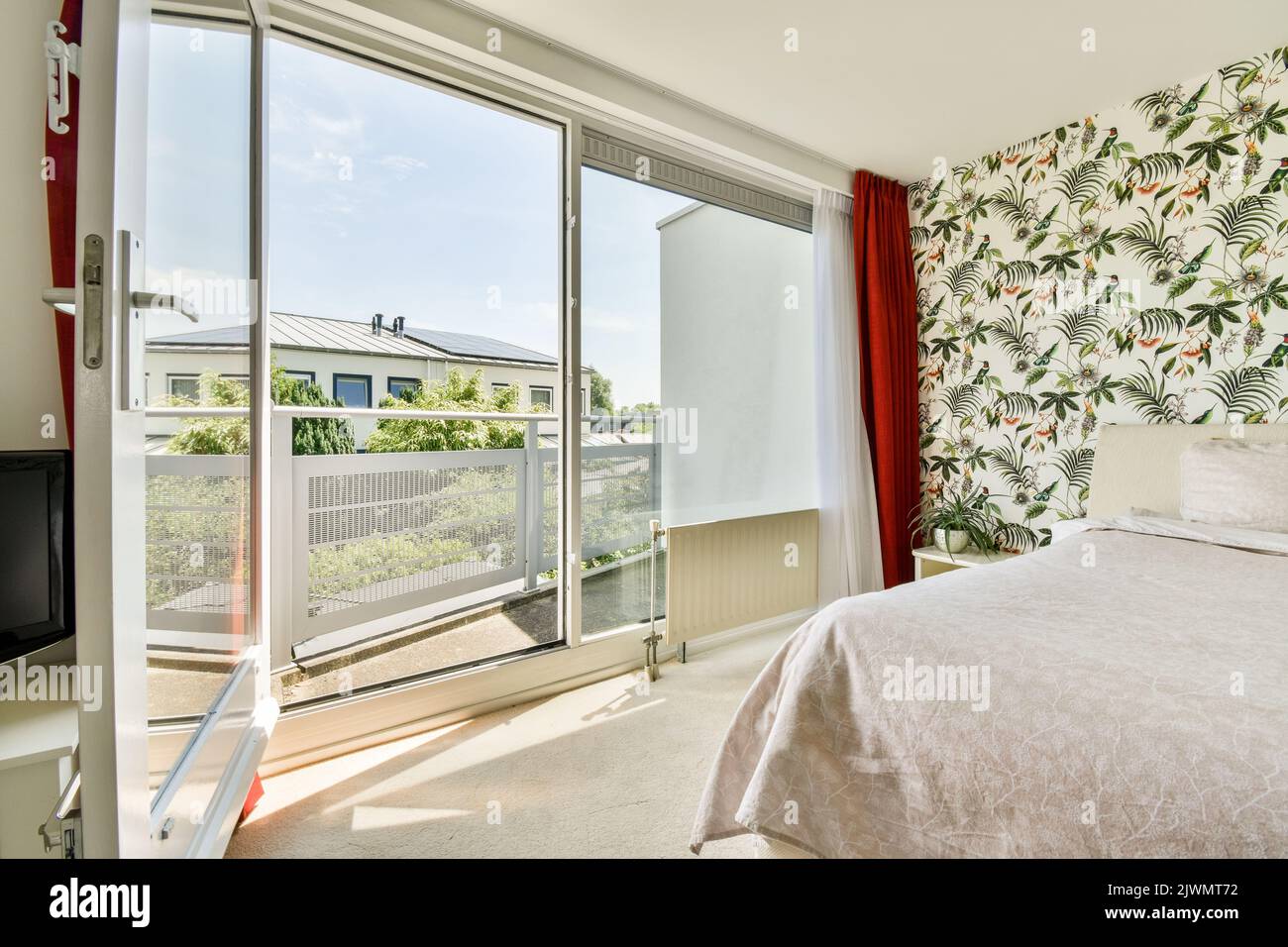 Comfortable bed located near window with curtain in light bedroom of ...