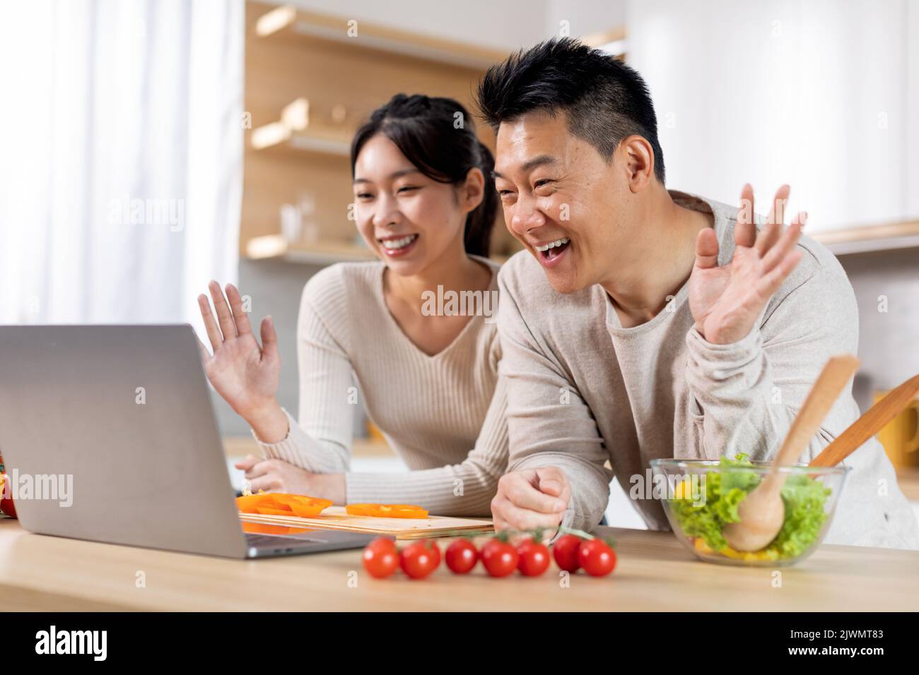 Happy asian couple having video chat while cooking at kitchen Stock ...