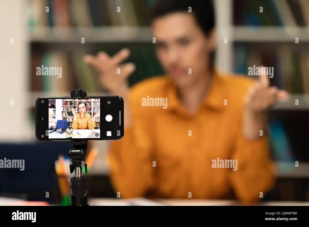 Mixed race female teacher recording online lesson using smartphone on ...