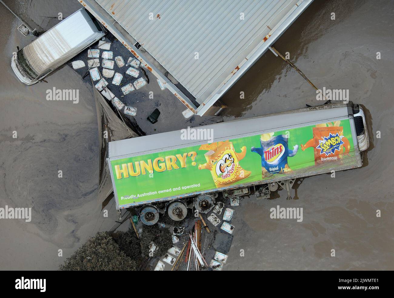 A food transport trailer lays on its side in mud as the floodwaters ...