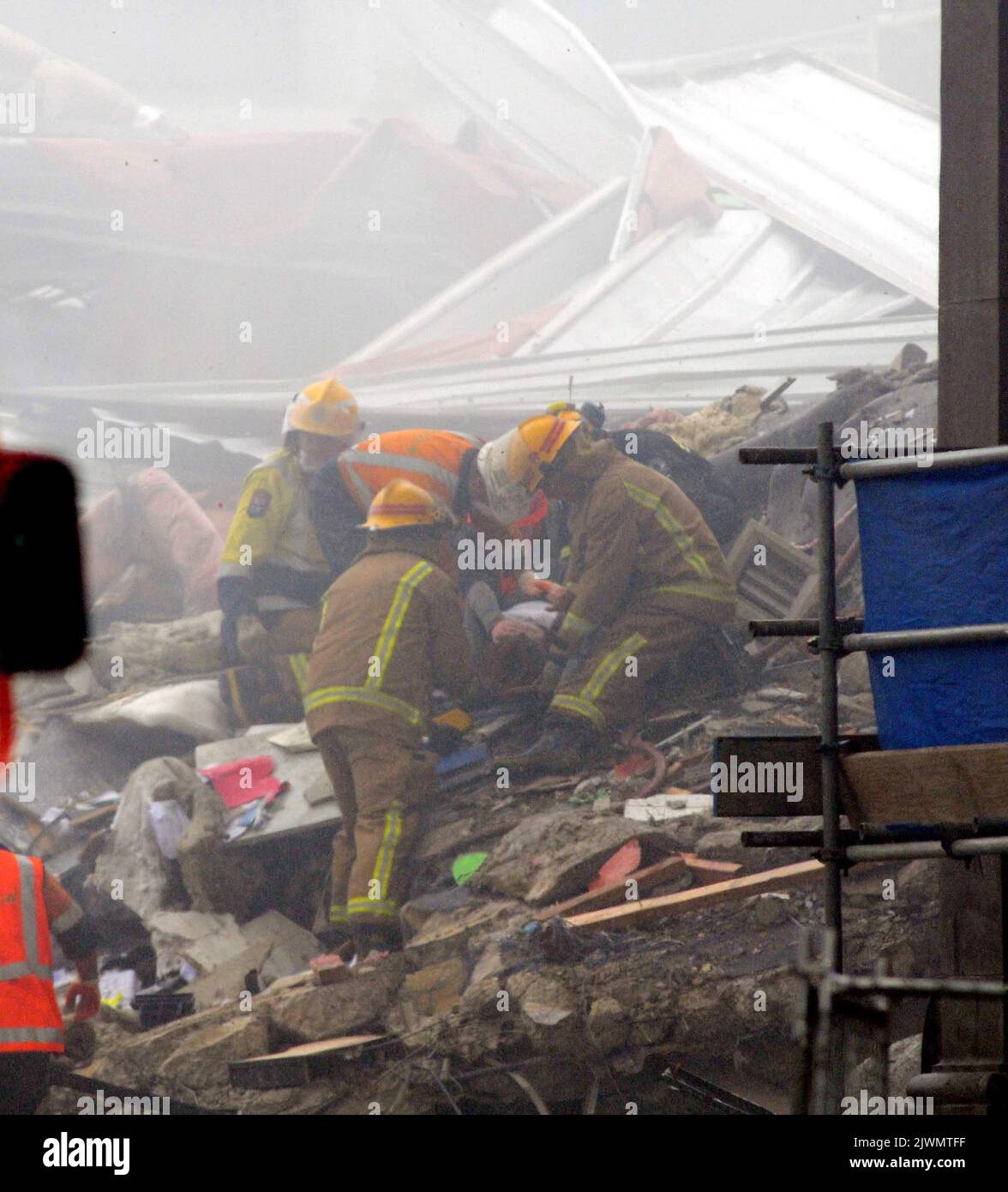 An injured woman is carried from the rubble of a collapsed multi-level ...