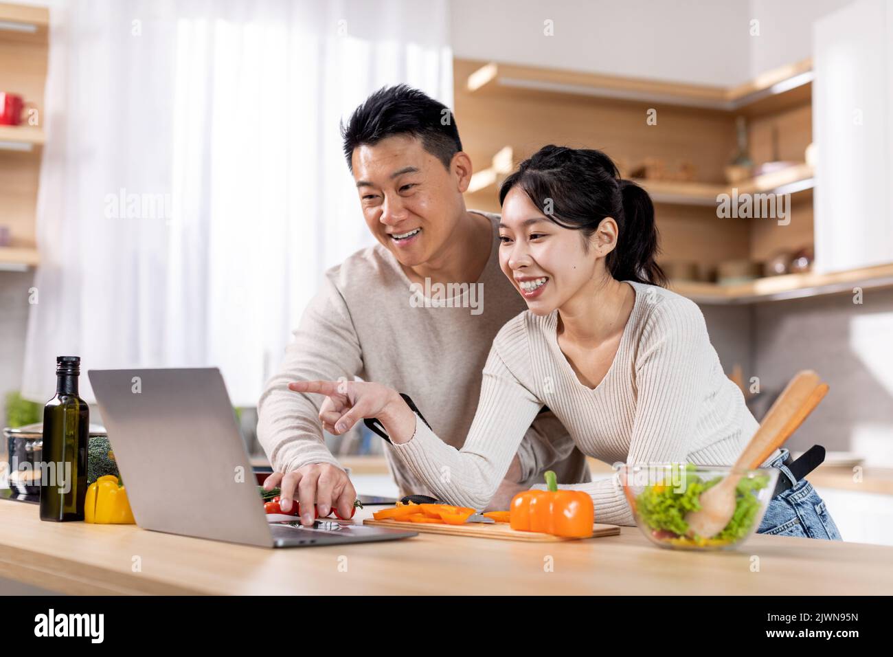 Positive japanese spouses watching culinary vlog while cooking Stock ...