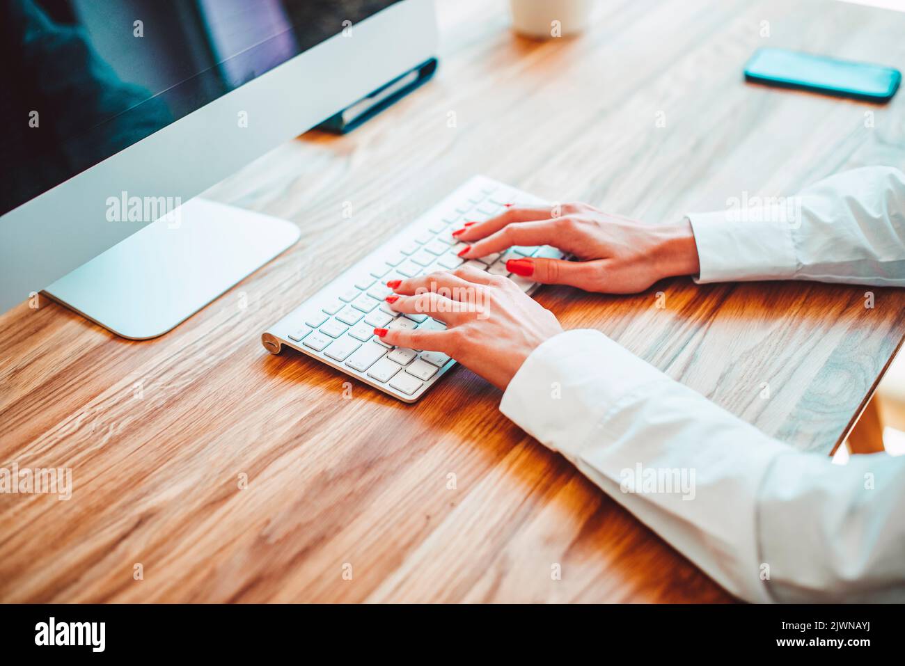 Side view of female hand typing on computer keyboard. Woman wearing red ...