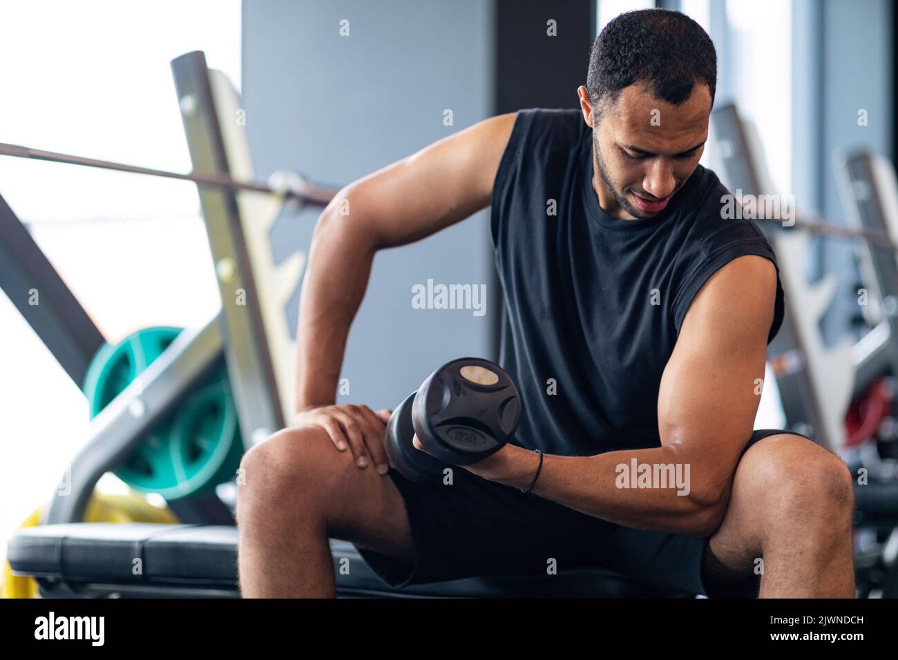 Muscular man lifting dumbbell sitting hi-res stock photography and ...