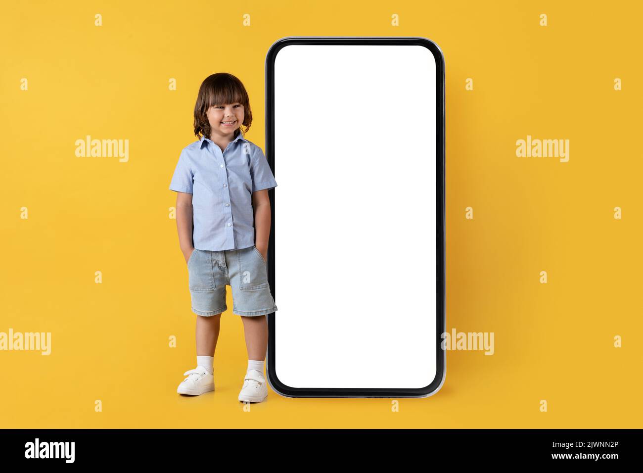 Cute happy little boy smiling to camera, posing near big blank ...