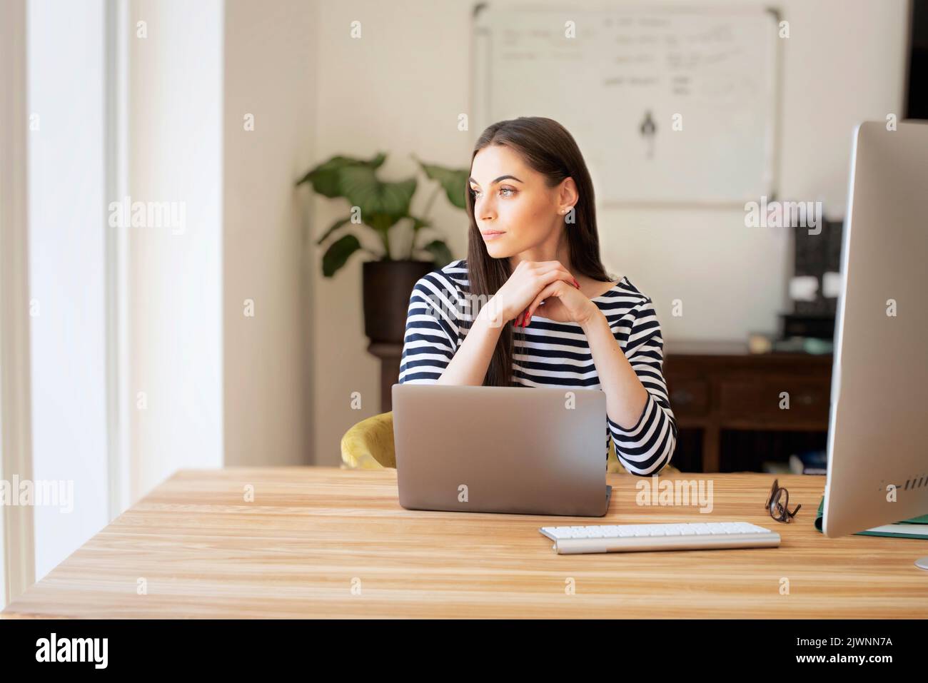 Beautiful woman looking out the window while sitting at desk behind her ...