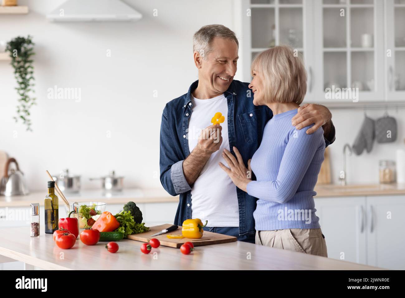 Loving senior husband feeding his pretty wife while cooking Stock Photo ...