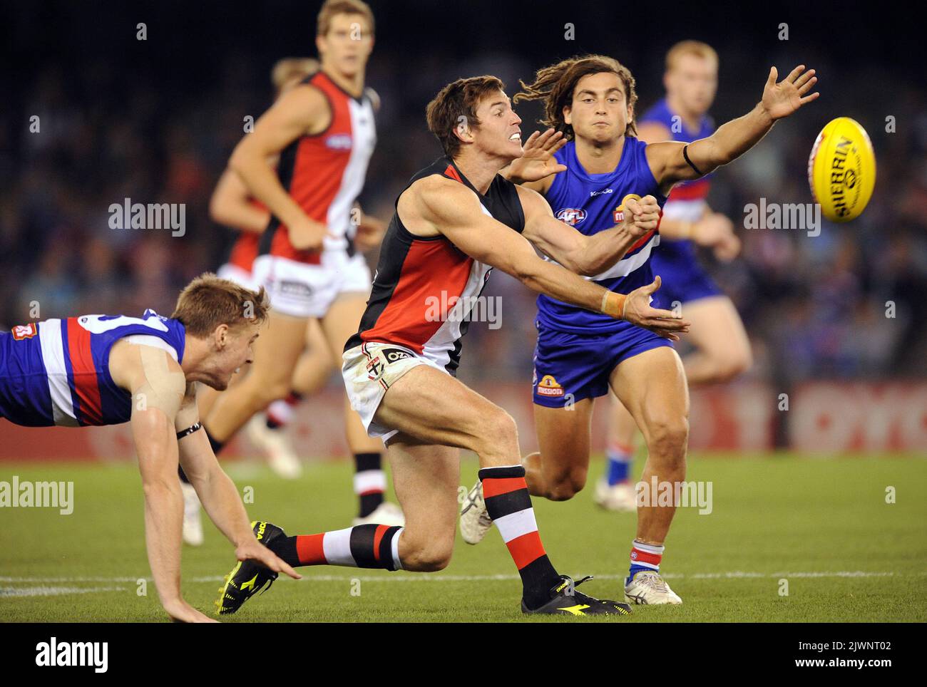 Lenny Hayes of St Kilda passes to a team-mate as he's tackled by Luke ...