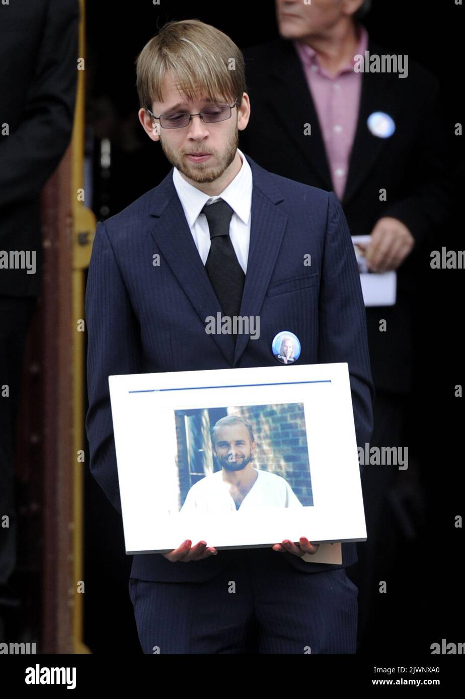 The son of Greg Ham, Max, carries a photo portrait of his father from ...