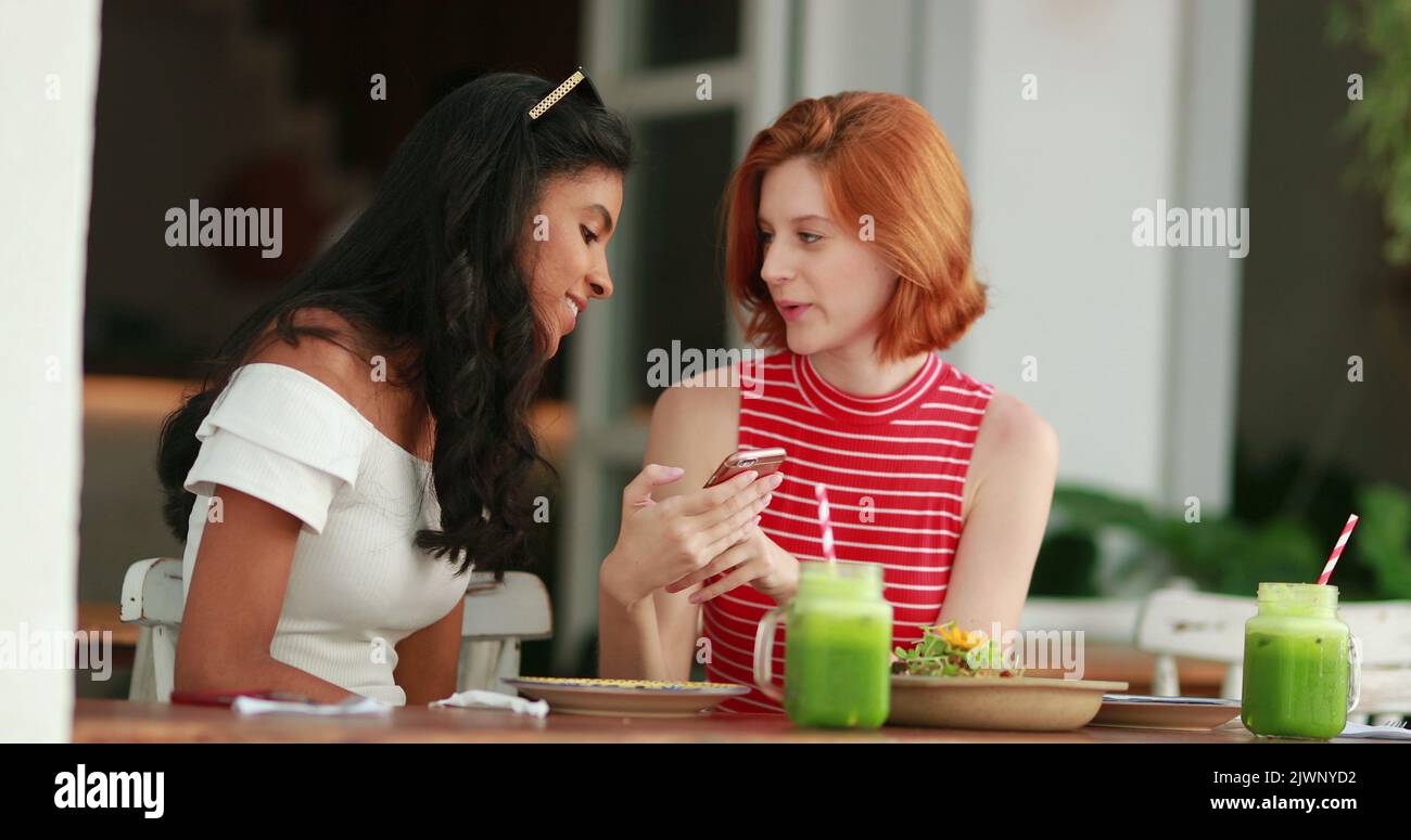 Multicultural friends hanging out together, young woman taking photo of ...