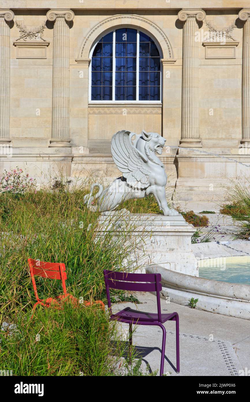 A statue of a griffin spouting water in a small pond in the gardens of ...